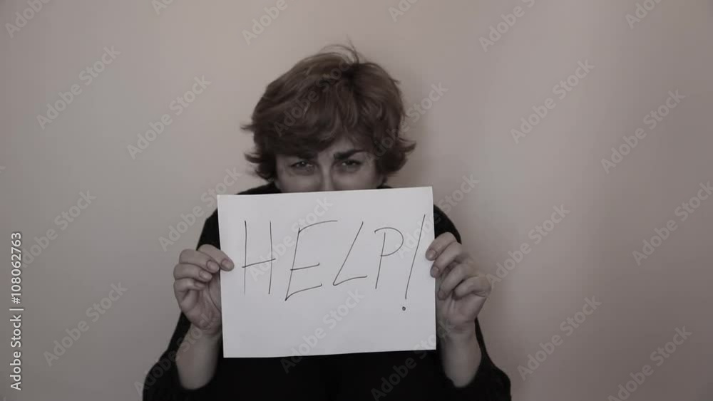 Scared and abused woman. When the light comes on she shows the paper ...