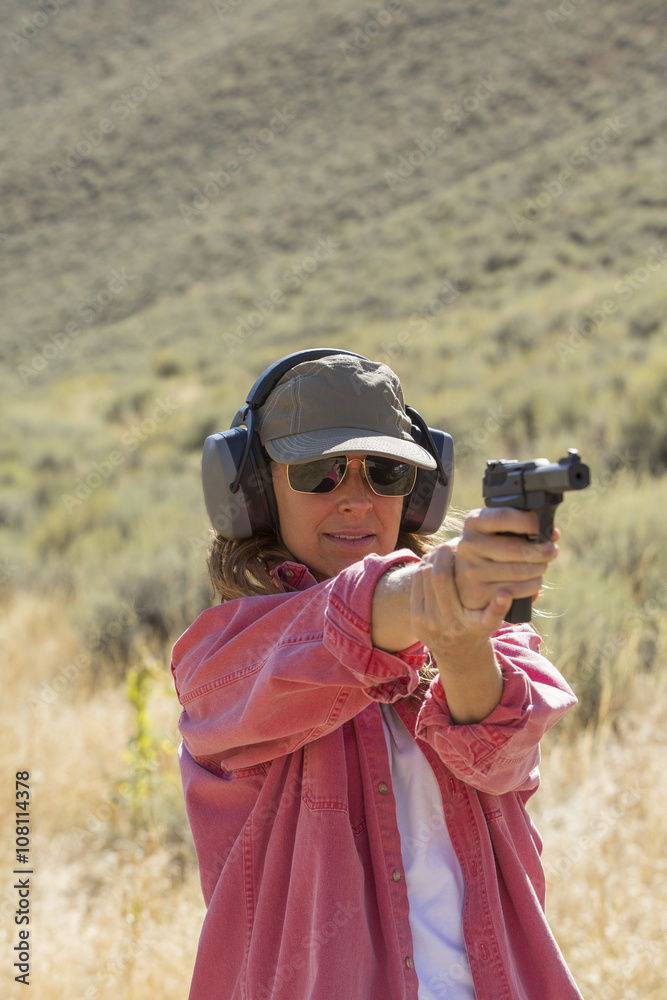 Foto Stock Caucasian woman aiming gun outdoors | Adobe Stock