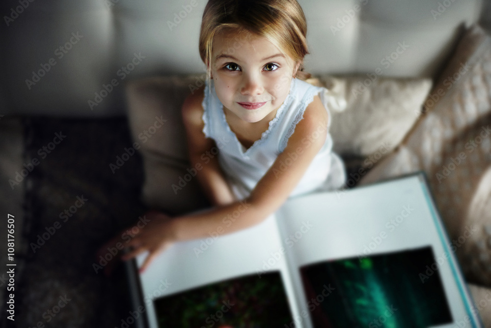 Caucasian girl reading book on sofa Stock Photo | Adobe Stock