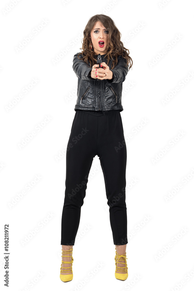 Scared woman shooting a gun at camera. Full body length portrait ...