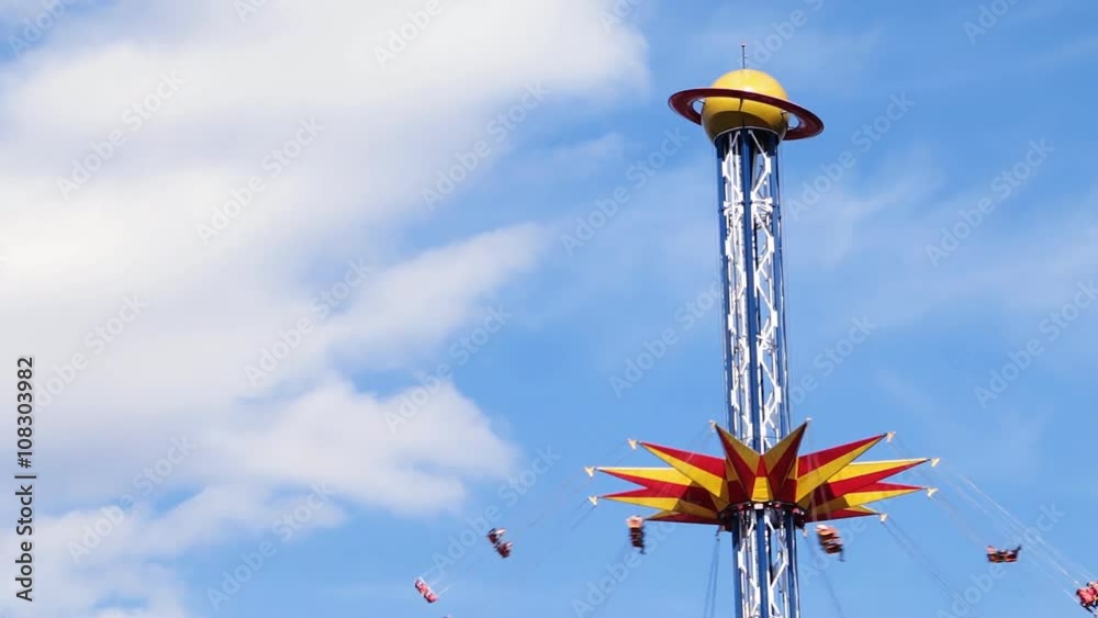 Rotating and lifting carnival ride with people kicking up legs against ...