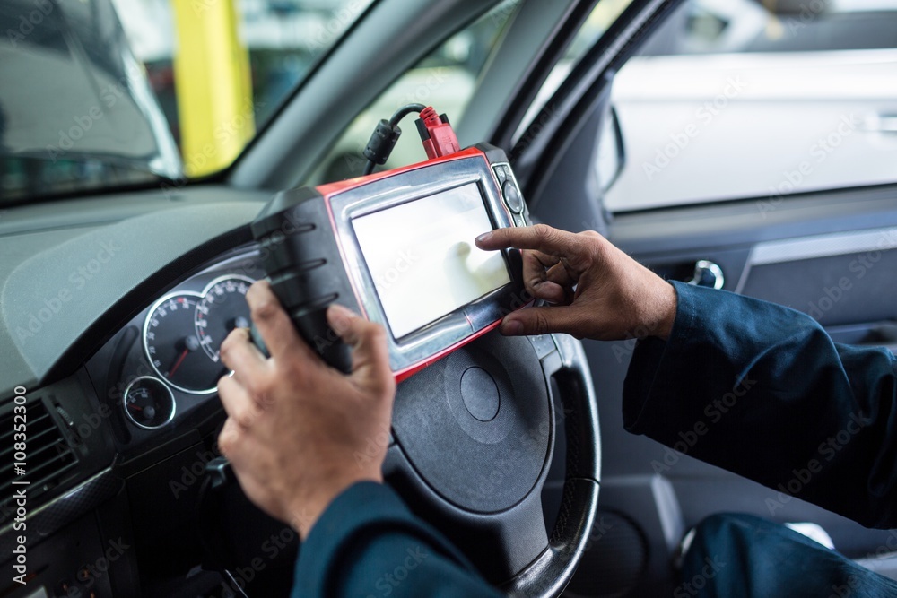 Mechanic using a diagnostic tool Stock Photo | Adobe Stock