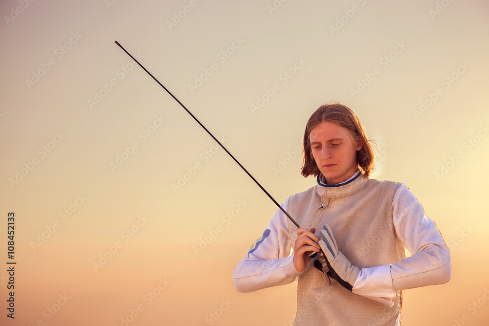 Fencer man wearing white fencing costume holding his sword in both ...
