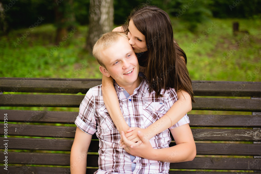 Young teen couple sitting together and lovely hugging on the bench ...