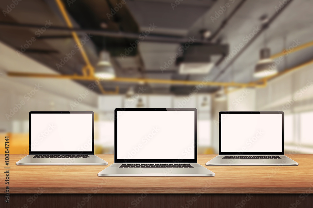 Three laptop devices on table in office interior. Isolated white screen ...