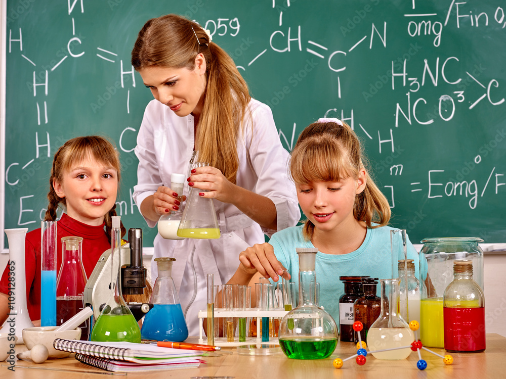 Teacher with children holding flask in chemistry class. Studies of ...