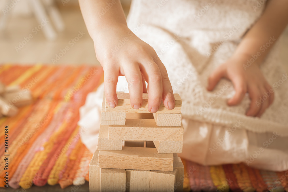 Child hands playing with wooden blocks the unstable tower. Building ...