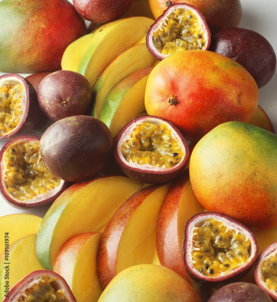 Stack of tropical fruit with mangoes and passion fruit, sliced and ...