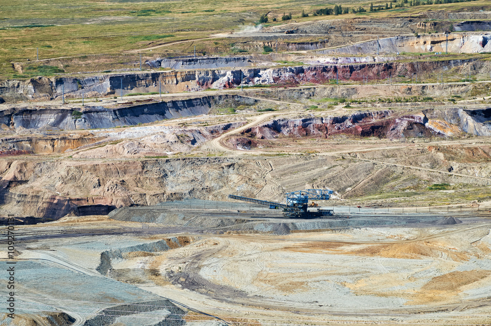 Pit mine with blue excavator at the bottom of the pit, and the storey ...