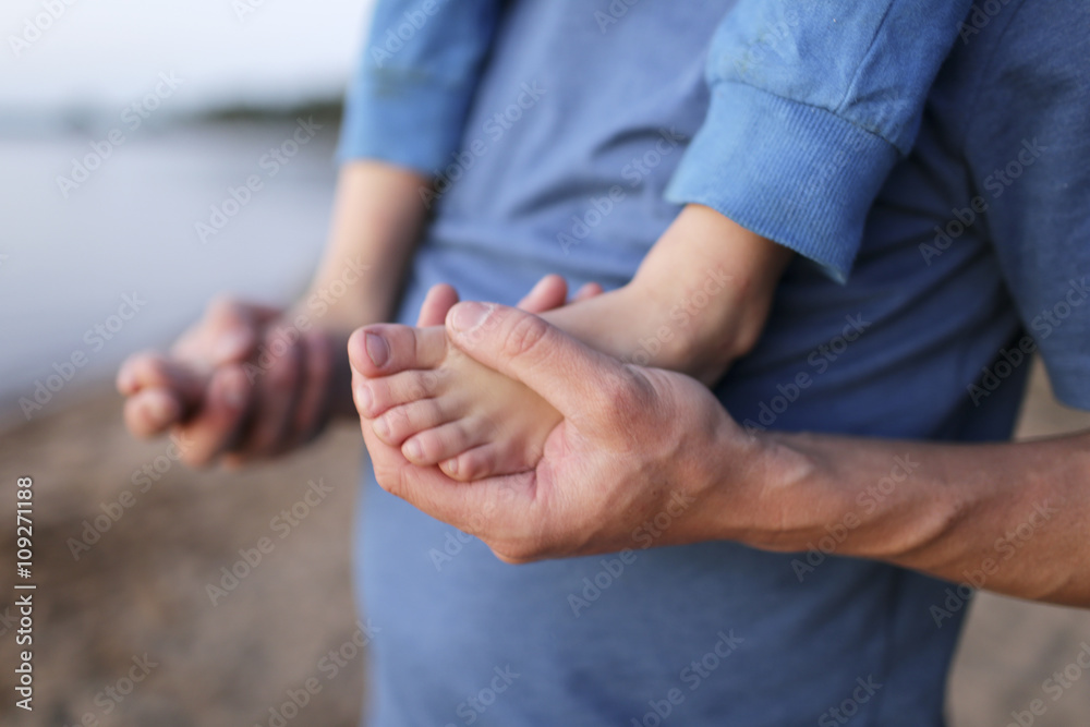 Mans hand holding childs foot Stock Photo | Adobe Stock