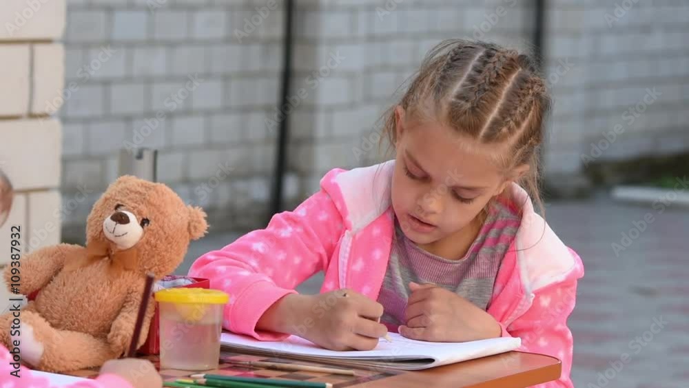 Seven-year girl with enthusiasm draws a pencil on the album, doing ...