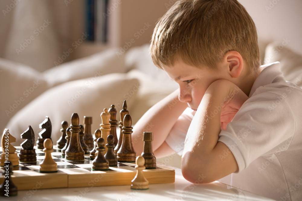 Boy playing chess in the room. Little clever boy concentrated and ...