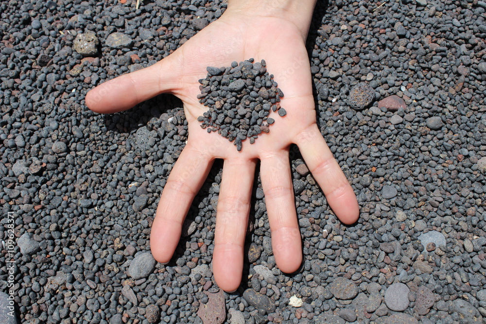 Granos de arena negra volcánica sobre la mano Stock Photo | Adobe Stock