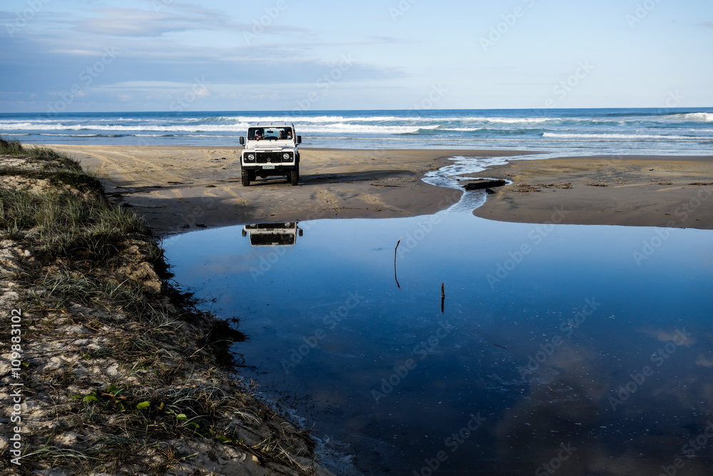 Land Rover Defender preparing to cross a lake formed on the sand in ...