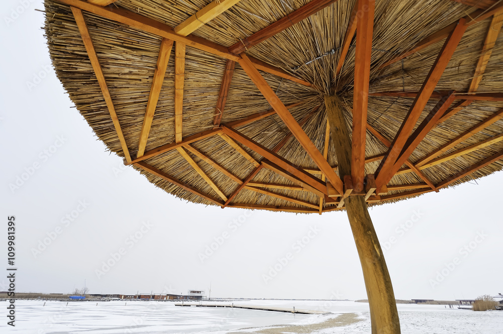 Schirm aus Schilf und Holz am Strand im Winter Stock Photo | Adobe Stock
