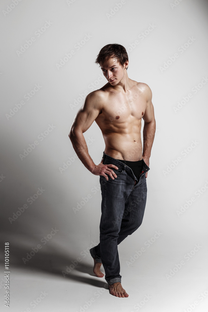 Muscular male model bodybuilder with unbuttoned jeans. Studio shot on ...