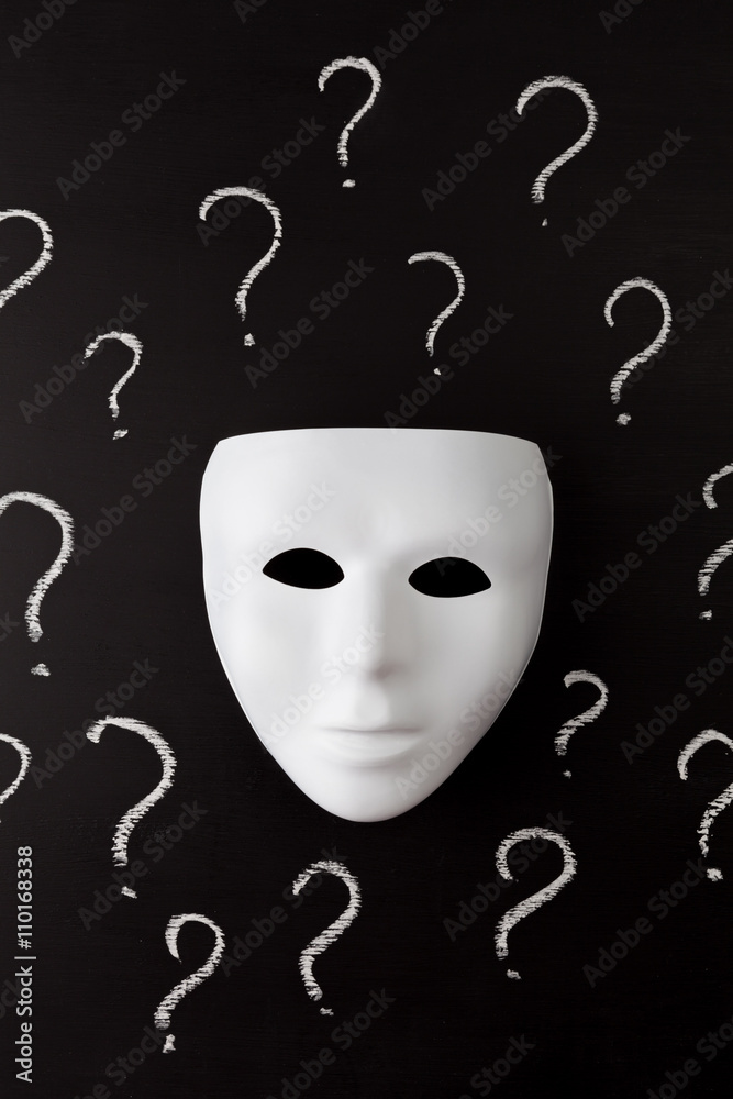 White mask on black background with hand drawn chalk question marks ...