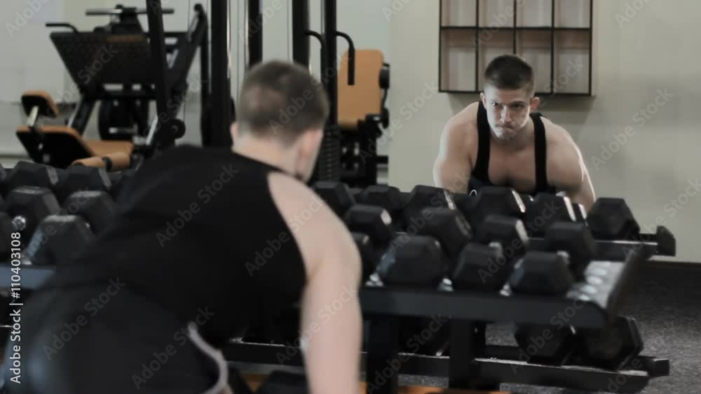 Muscular athlete trains with dumbbells Muscular man leaning on the arm ...