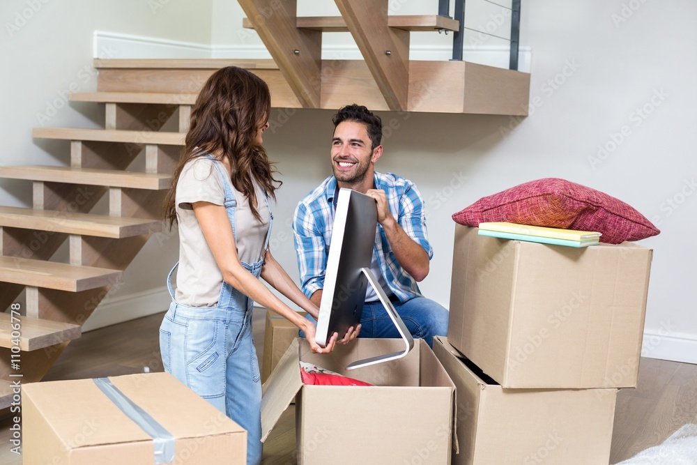Smiling couple unpacking computer from cardboard box Stock Photo ...