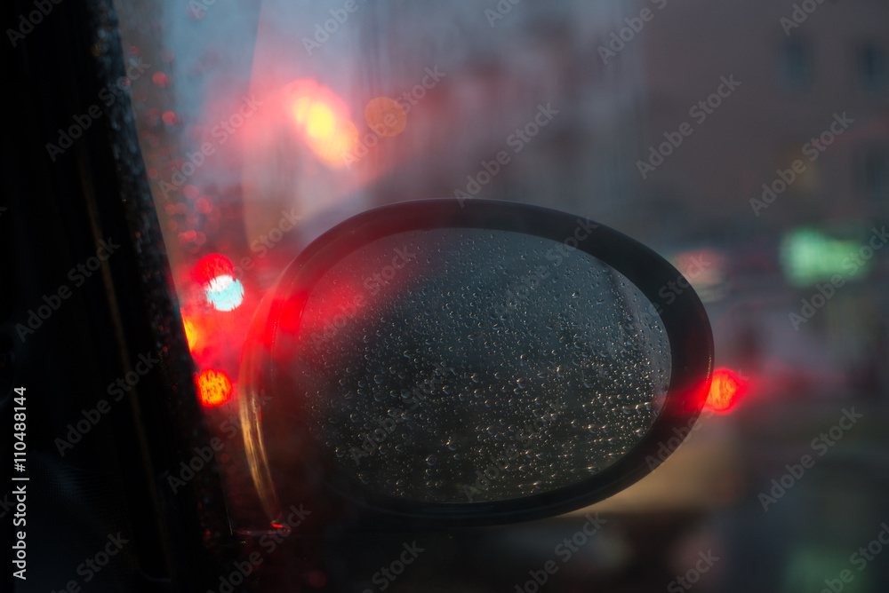 Blurred image of car side mirror. city street and traffic lights ...
