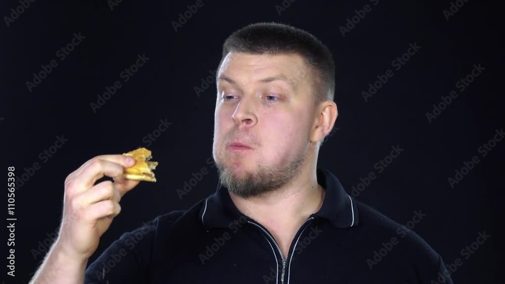 Man greedily eating hamburger. Black. Slow motion Stock Video | Adobe Stock