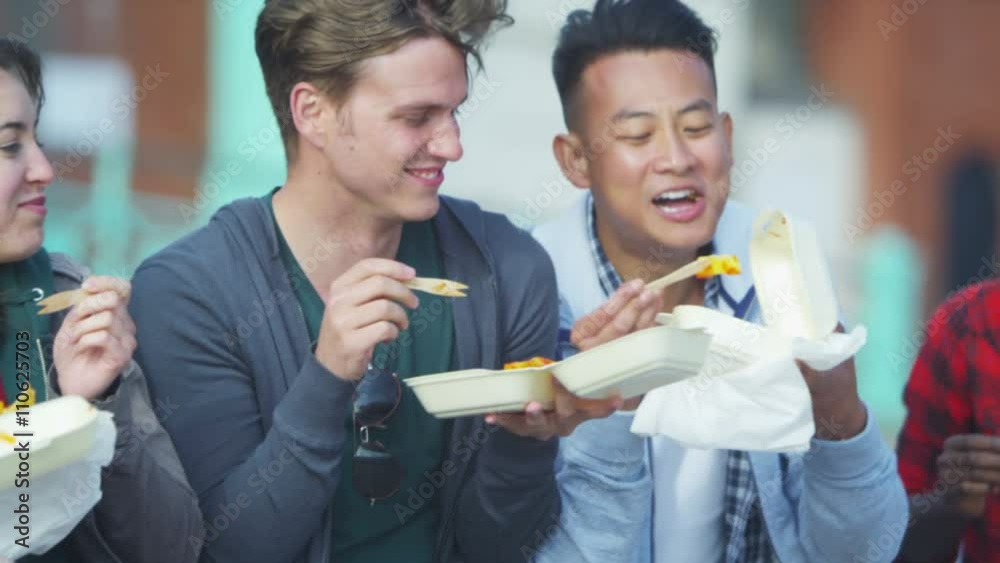 Happy mixed ethnicity group of friends eating fried chips in urban area ...