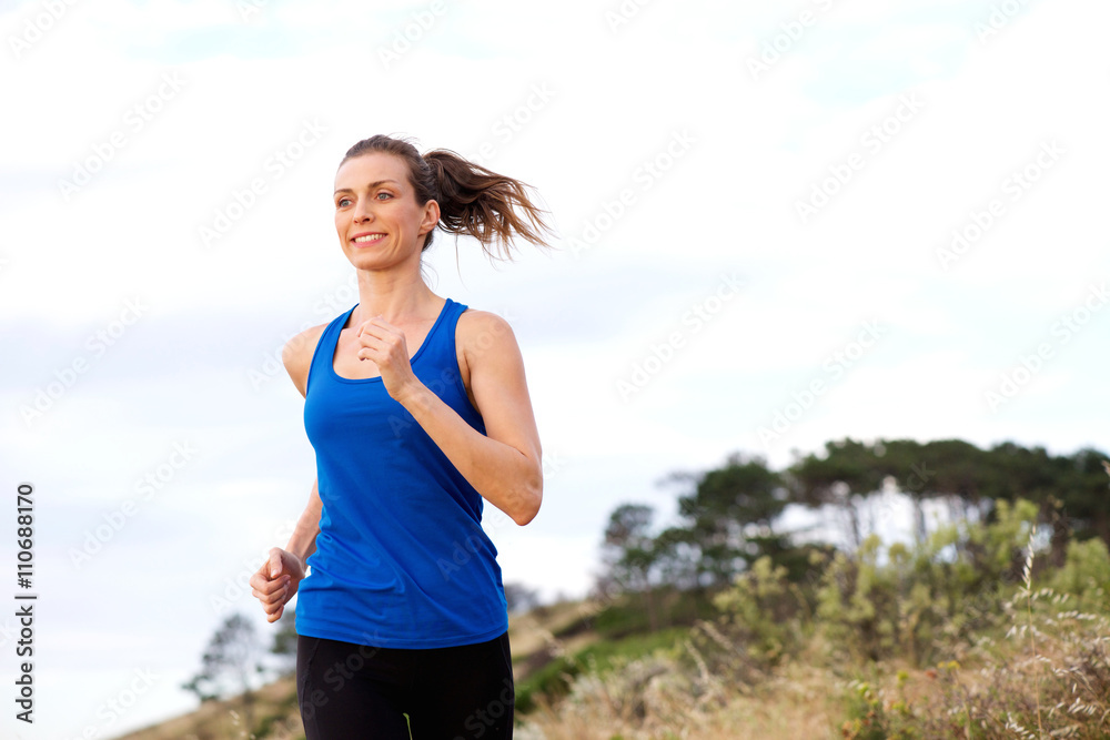 Smiling woman running outdoors in sportswear Stock Photo | Adobe Stock