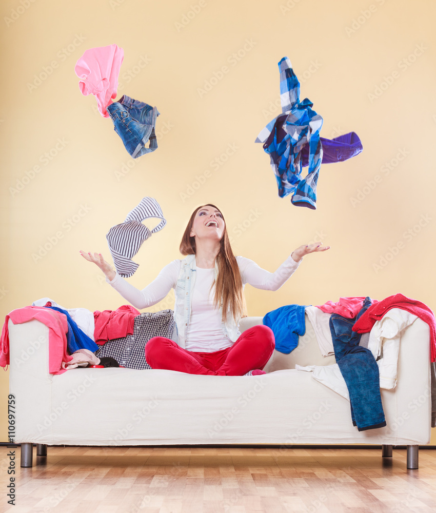 Happy woman on sofa in messy room throwing clothes Stock Photo | Adobe ...