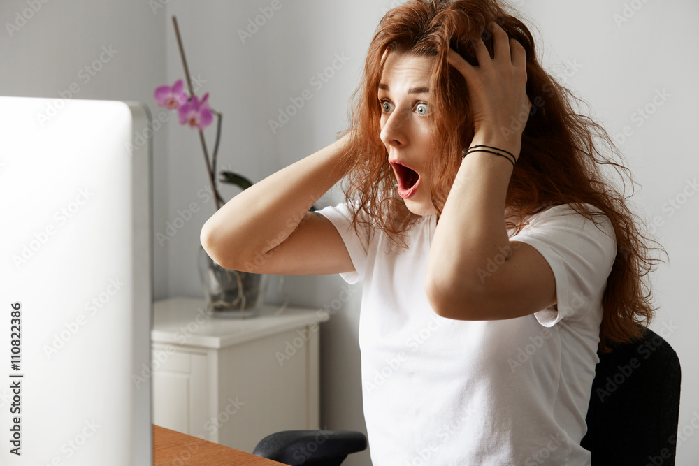 Pretty student girl having trouble with her laptop, looking in panic at ...