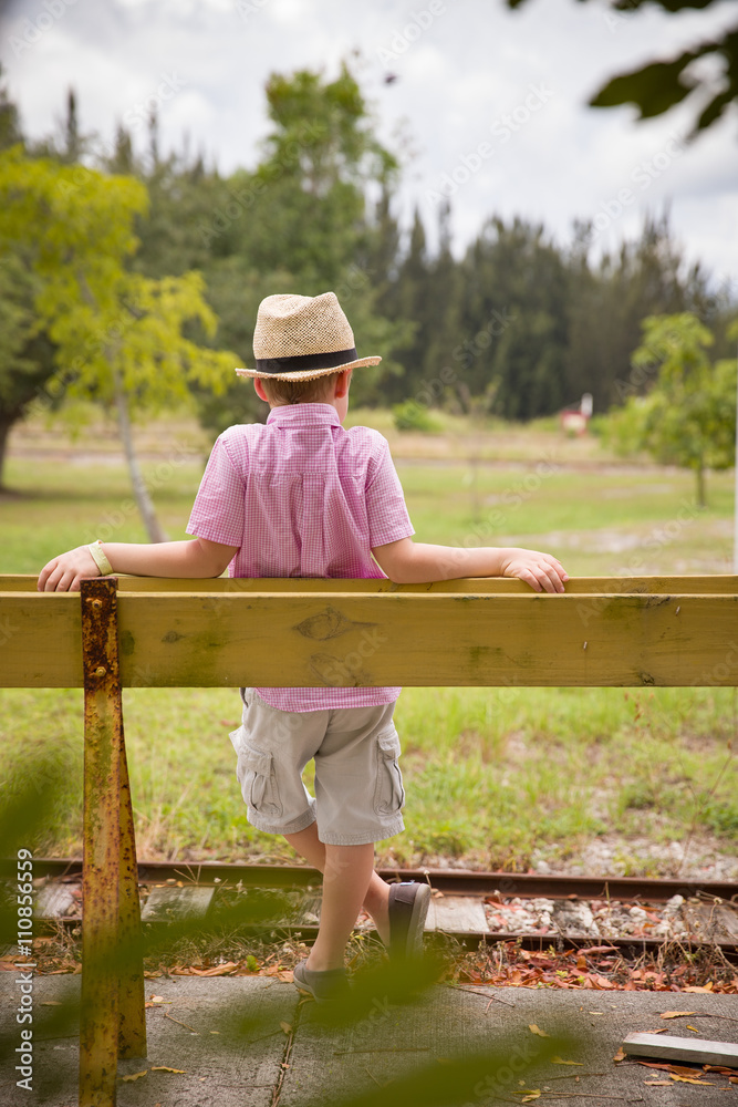 Foto de Cute kid boy in s a straw hat standing on either side of an old ...