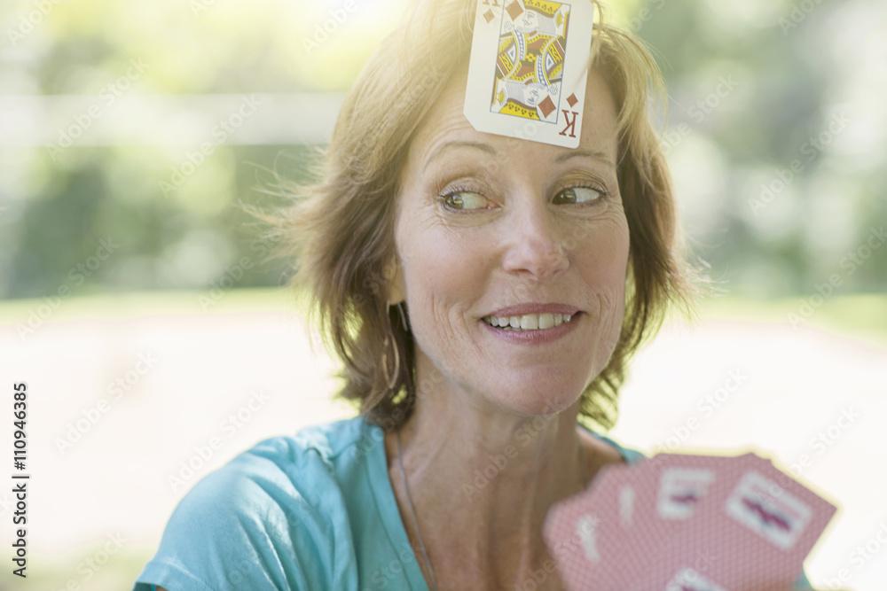 Mature woman playing cards, a playing card stuck on her forehead Stock ...