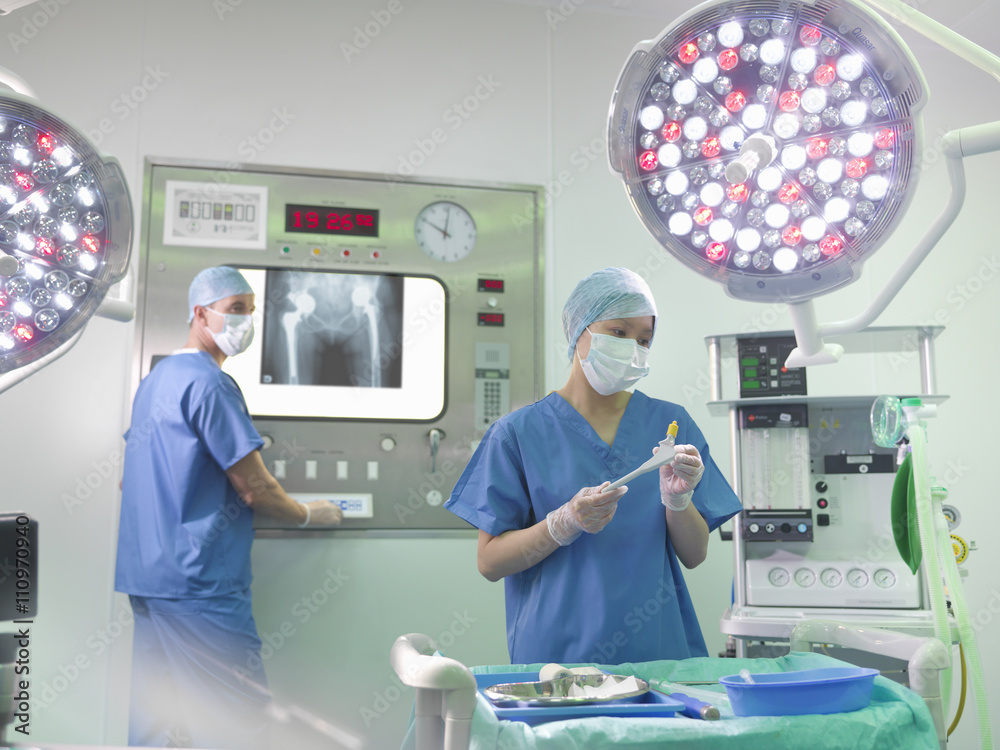 Orthopaedic surgeon and nurse with replacement hip stem in operating ...