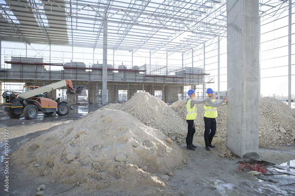 Builder and architect marking pillar with spray can on construction ...