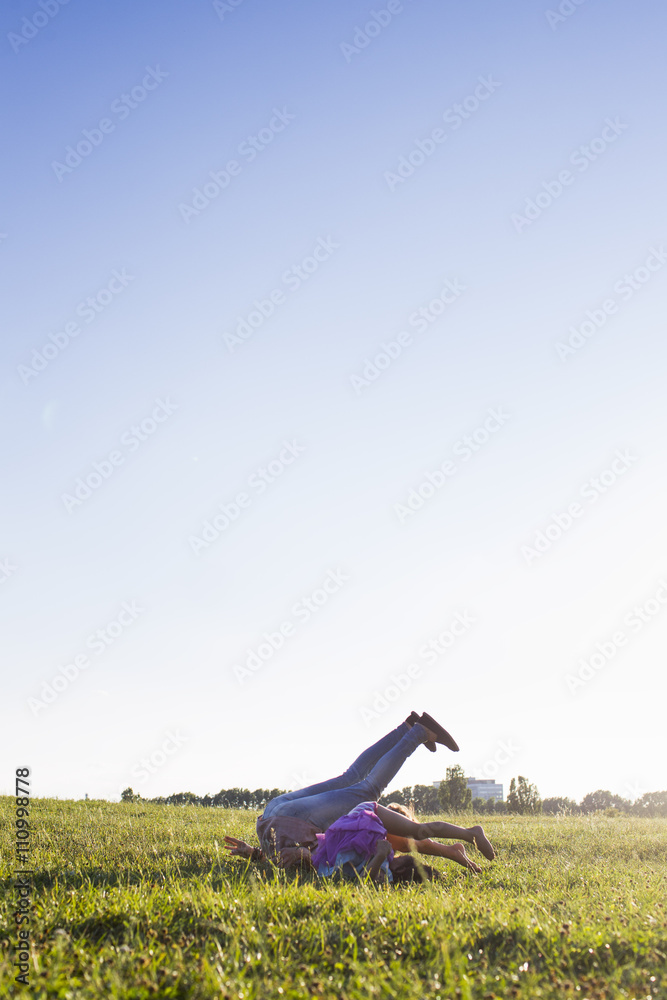 Mature woman and daughter rolling backwards in park Stock Photo | Adobe ...