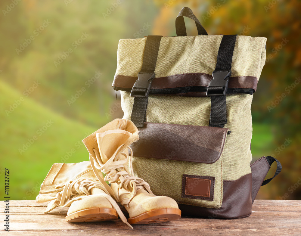 Tourism concept. Backpack and pair of boots on blurred nature ...