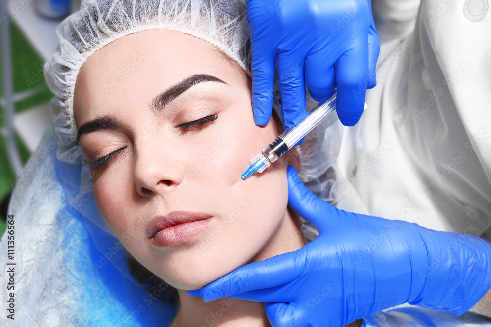 Young woman receiving plastic surgery injection on her face, closeup ...