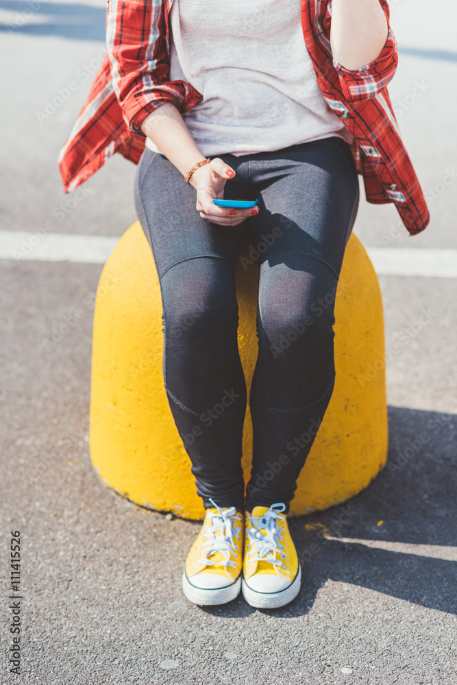From the neck down view of young woman sitting outdoor in the city ...