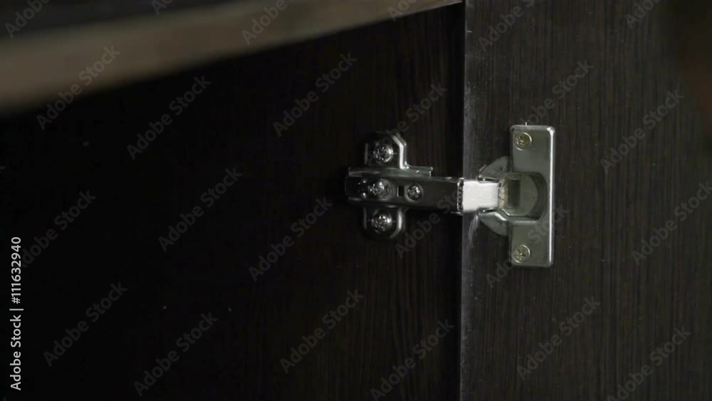 The worker is fastening the door hinge to the furniture detail using ...