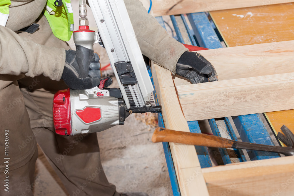 Building a wall for frame house.Worker use Framing Nailer to attach ...