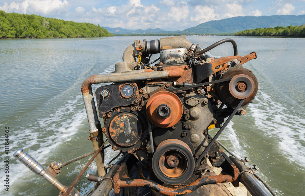 The engine of a long-tail boat with boat wake and tropical mangrove ...
