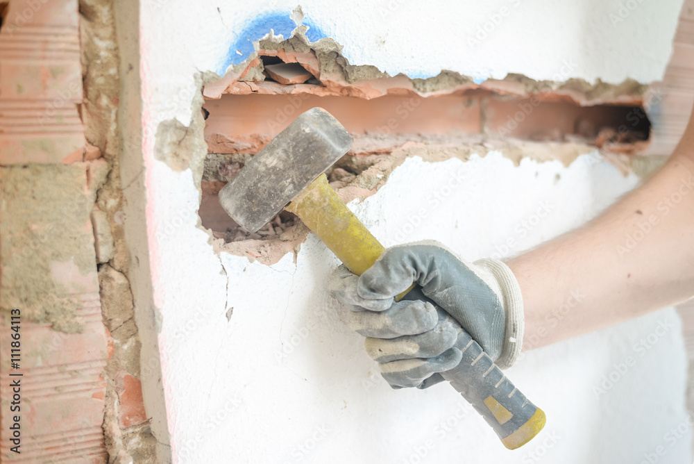 Closeup of hand holding hammer and breaking cement brick wall Stock ...