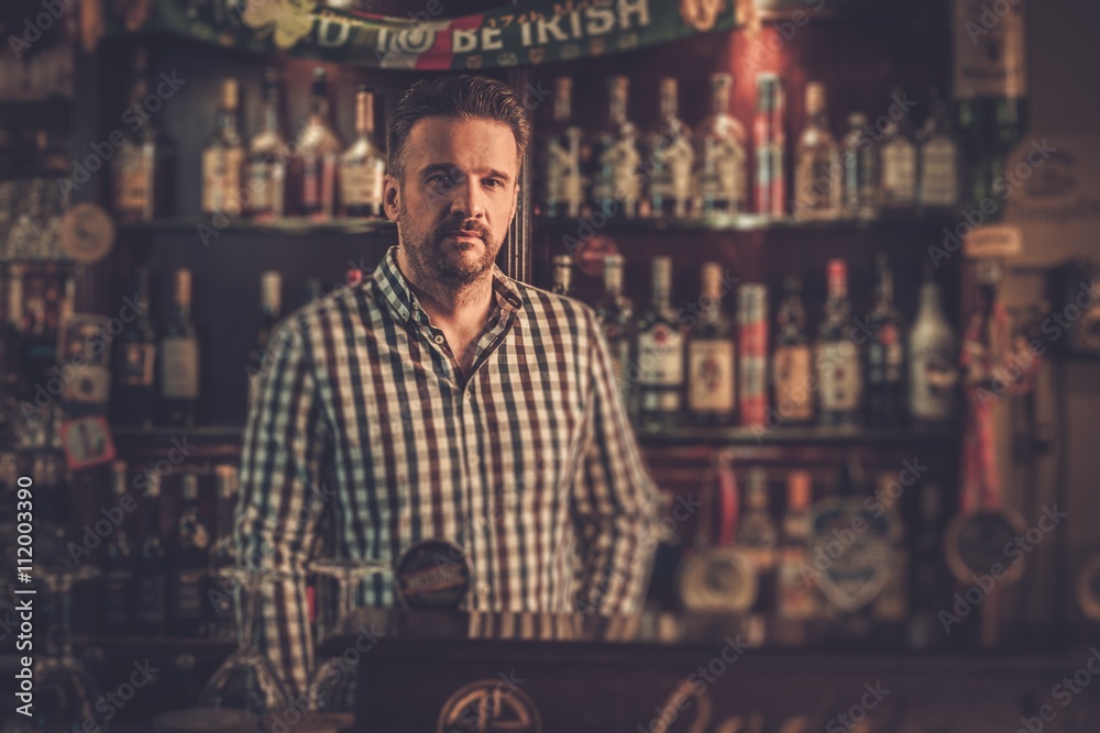 Handsome bartender standing at bar counter in his pub. Stock Photo ...