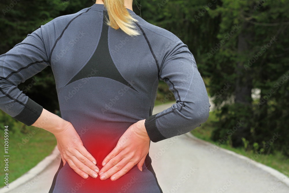 Back Pain. Athletic fitness woman rubbing the muscles of her lower back ...