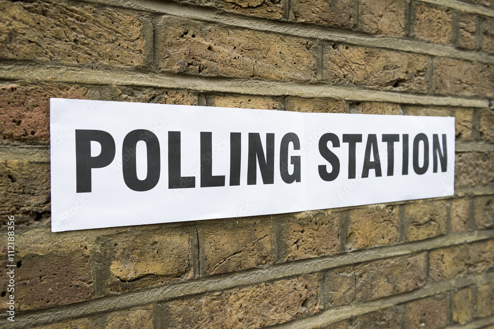 British election polling station sign hanging on classic yellow brick ...