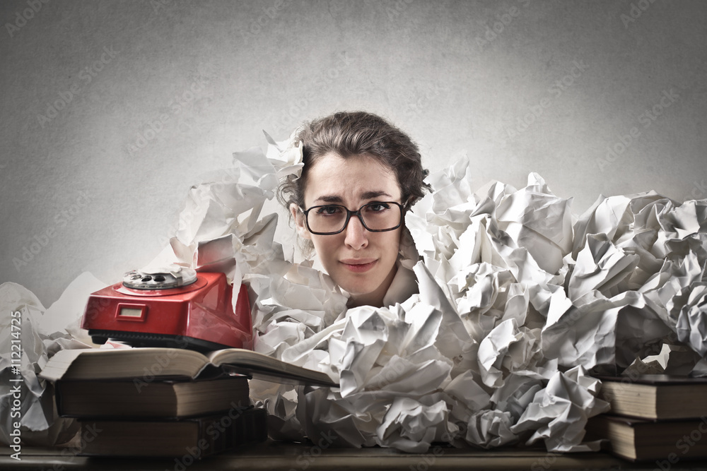 Writer surrounded by sheets of paper Stock Photo | Adobe Stock