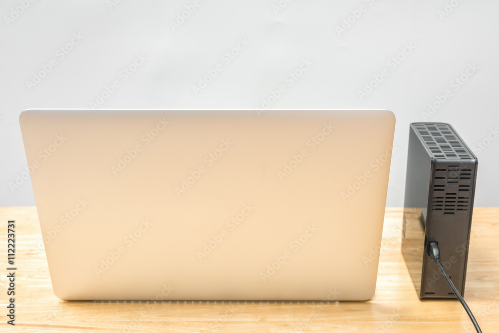 Laptop and external hard drive on office desktop with white wall ...