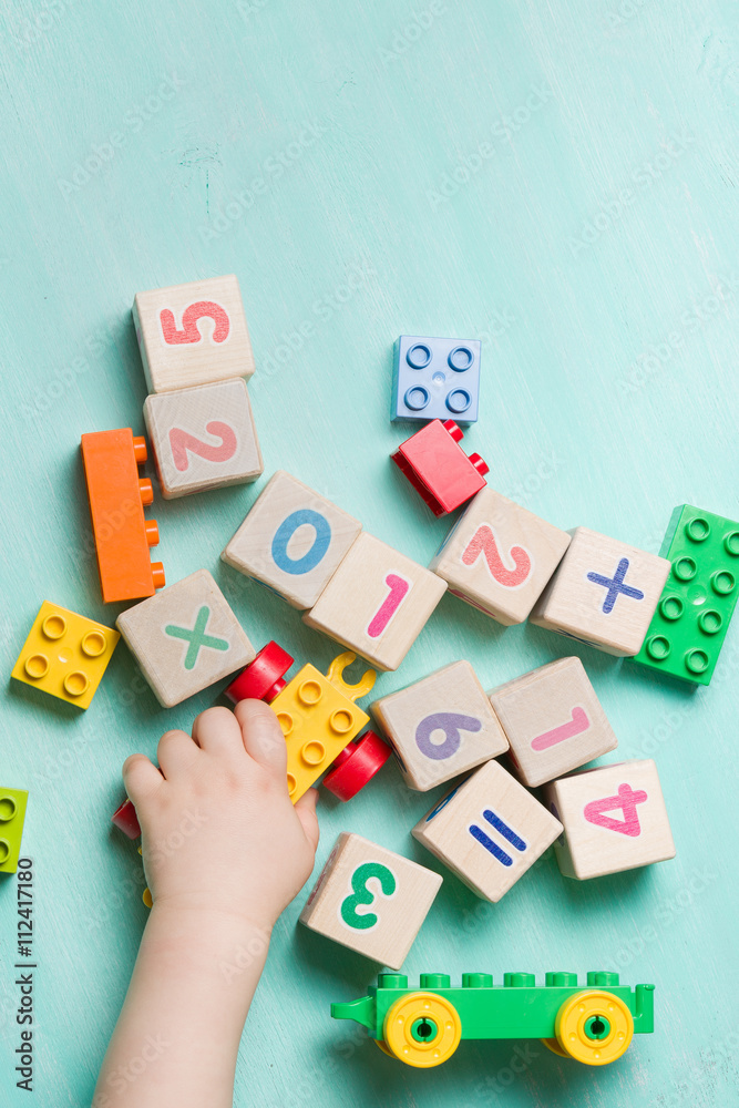 Child playing with wooden cubes with numbers and colorful toy bricks on ...