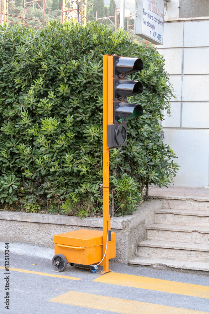 Mobile temporary yellow traffic light with a battery on the road in the ...