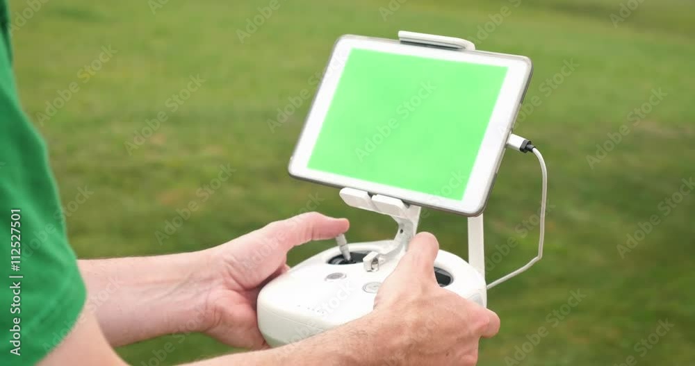 A man uses a RC controller for a drone or UAV outside in an open field ...