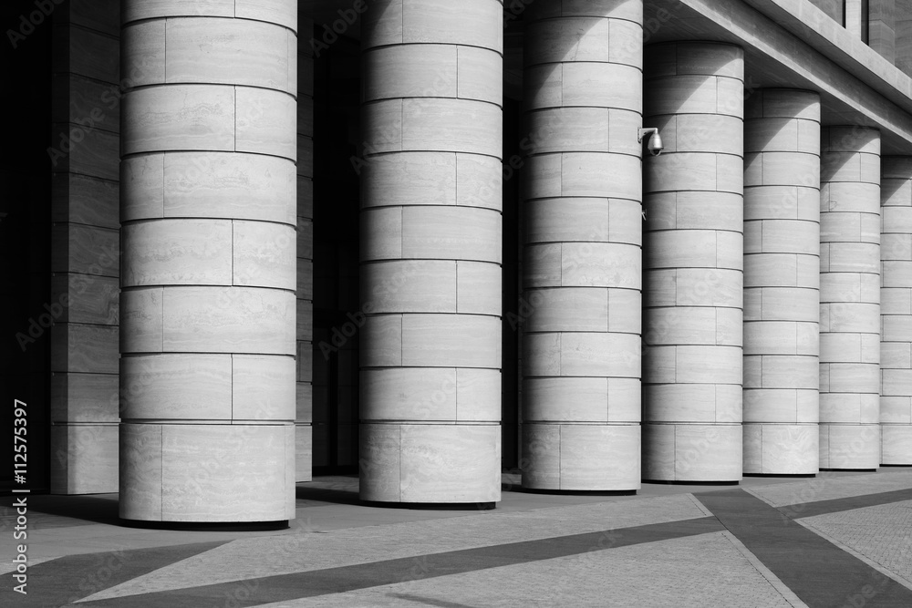 Row of marble columns with dark gaps and pavement floor. Black and ...